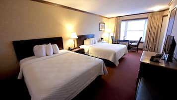 Quarto de hotel com duas camas, uma escrivaninha e uma cadeira.