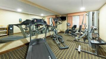Uma academia com esteiras, elípticos e equipamentos de musculação.
