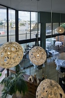 Um interior moderno com grandes janelas, móveis de madeira e luminárias pendentes.