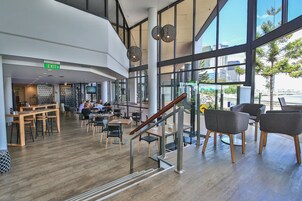 Interior moderno com escada, áreas de estar e sinalização de saída.