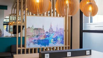 Quarto de hotel moderno com divisória de madeira, uma pintura de paisagem urbana e três luminárias pendentes esféricas.