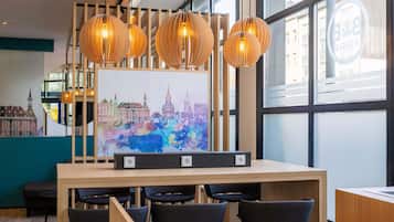 Um hall de hotel moderno com uma mesa de recepção de madeira, cadeiras pretas e uma pintura colorida com vista para a cidade.