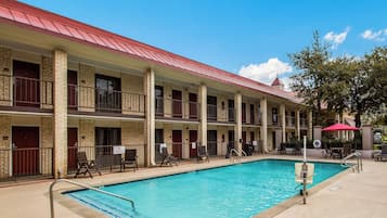 Um hotel com piscina, várias varandas e área de estar ao ar livre.