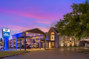 Um hotel Best Western com área de estacionamento coberta e um edifício de pedra com janelas em arco.