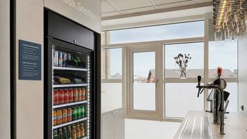 Quiosque com máquina automática de bebidas, abastecida com diversas opções.