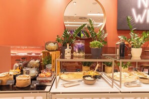 Disposição de buffet com diversos alimentos e um espelho refletindo o ambiente.