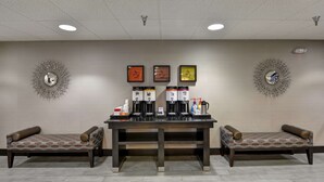 Um hall de hotel com uma mesa comprida, dois sofás e um espaço para café.