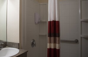 Um banheiro com pia branca, espelho, cortina de chuveiro e porta-toalhas.