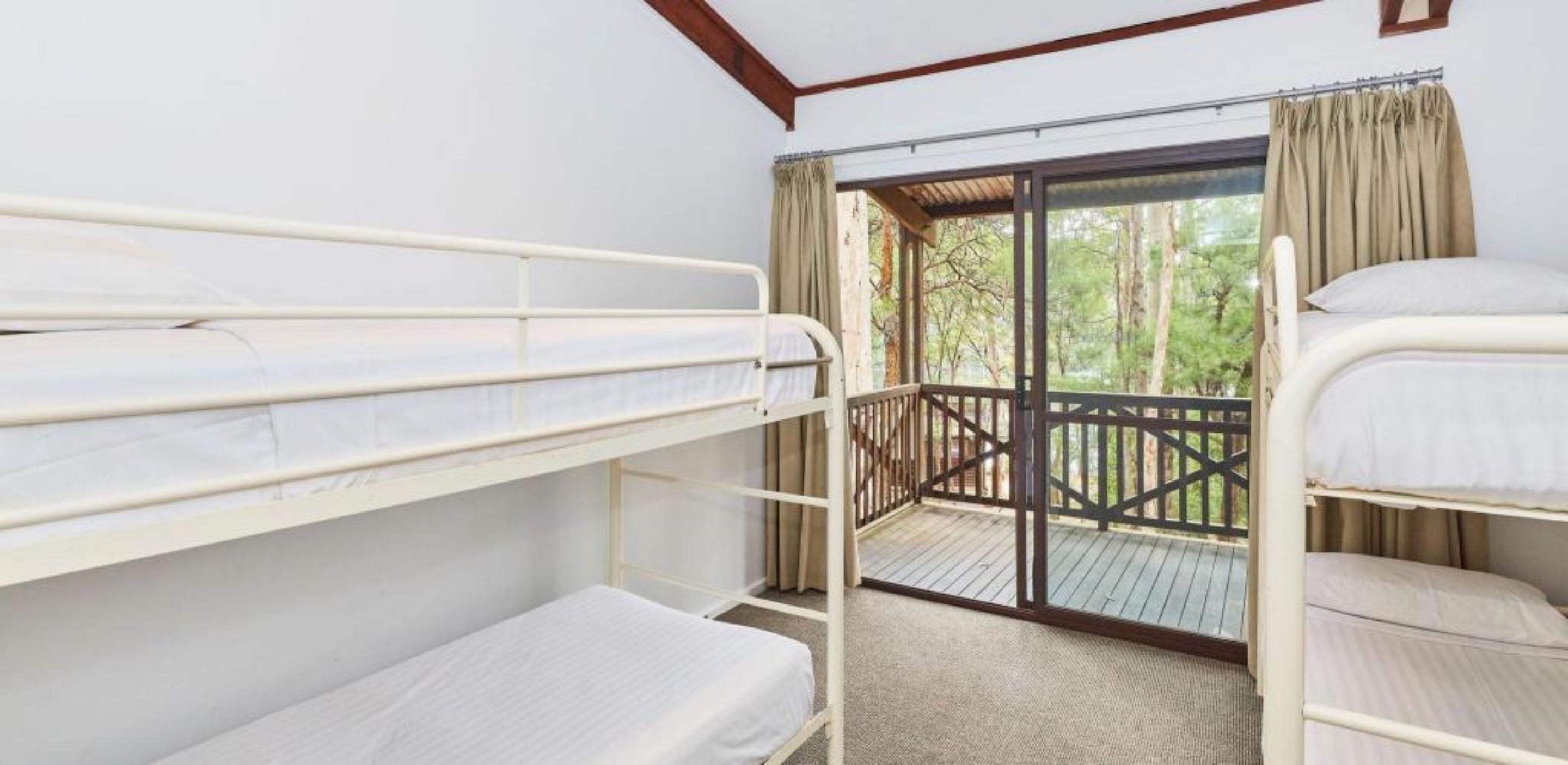 Quarto com beliches, deck de madeira e vista para árvores.