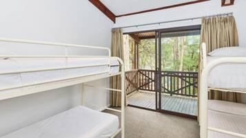 Quarto com beliches, deck de madeira e vista para árvores.