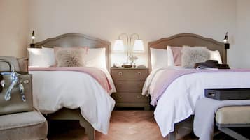 Quarto de hotel com duas camas, uma cômoda e uma cadeira.