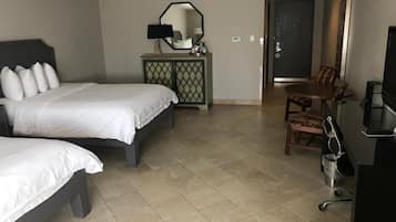 Quarto de hotel com duas camas, uma mesa pequena com uma cadeira, uma televisão e uma porta.