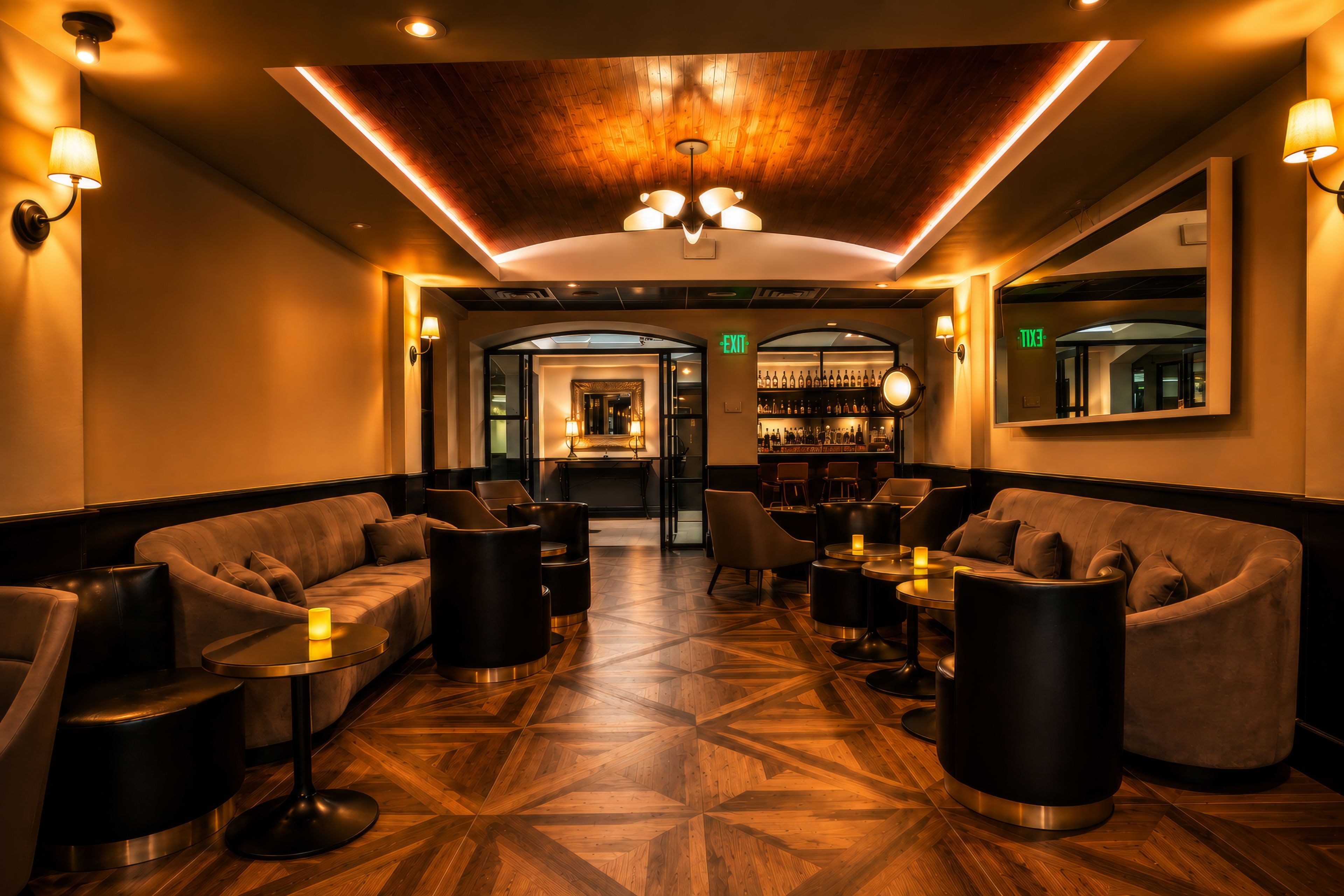 Um saguão de hotel com sofás de couro, mesas redondas e um bar com parede espelhada.