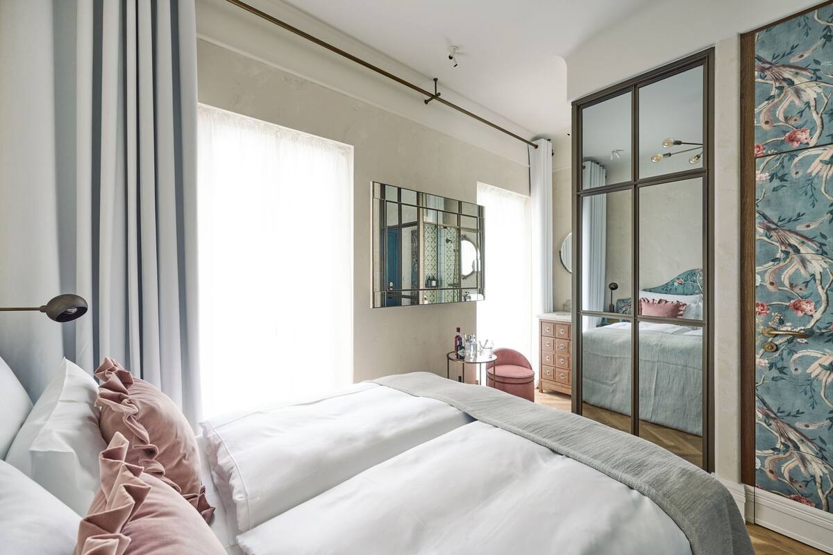 Quarto com cama, espelho, guarda-roupa e uma mesinha.