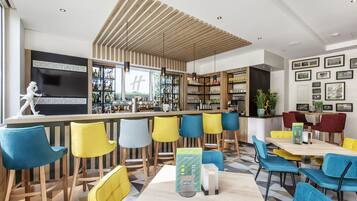 Uma área de bar moderna com ripas de madeira no teto, balcão repleto de garrafas e banquetas coloridas.
