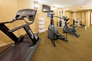 Centro de fitness do hotel com aparelhos de cardio, televisão e suporte para toalhas.