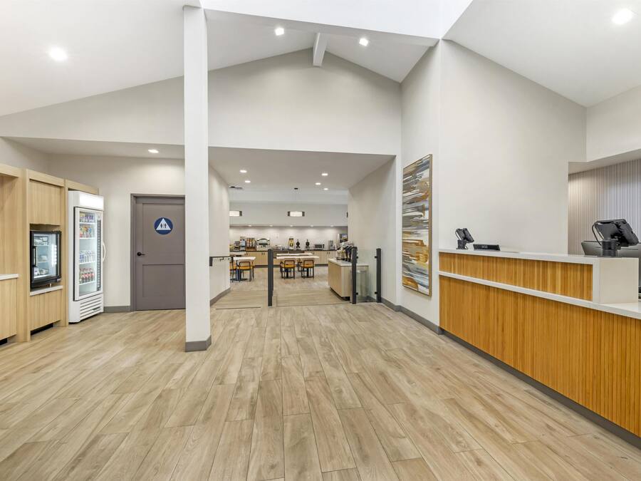 Um hall espaçoso com uma mesa de recepção de madeira, um frigorífico e uma máquina de vendas.