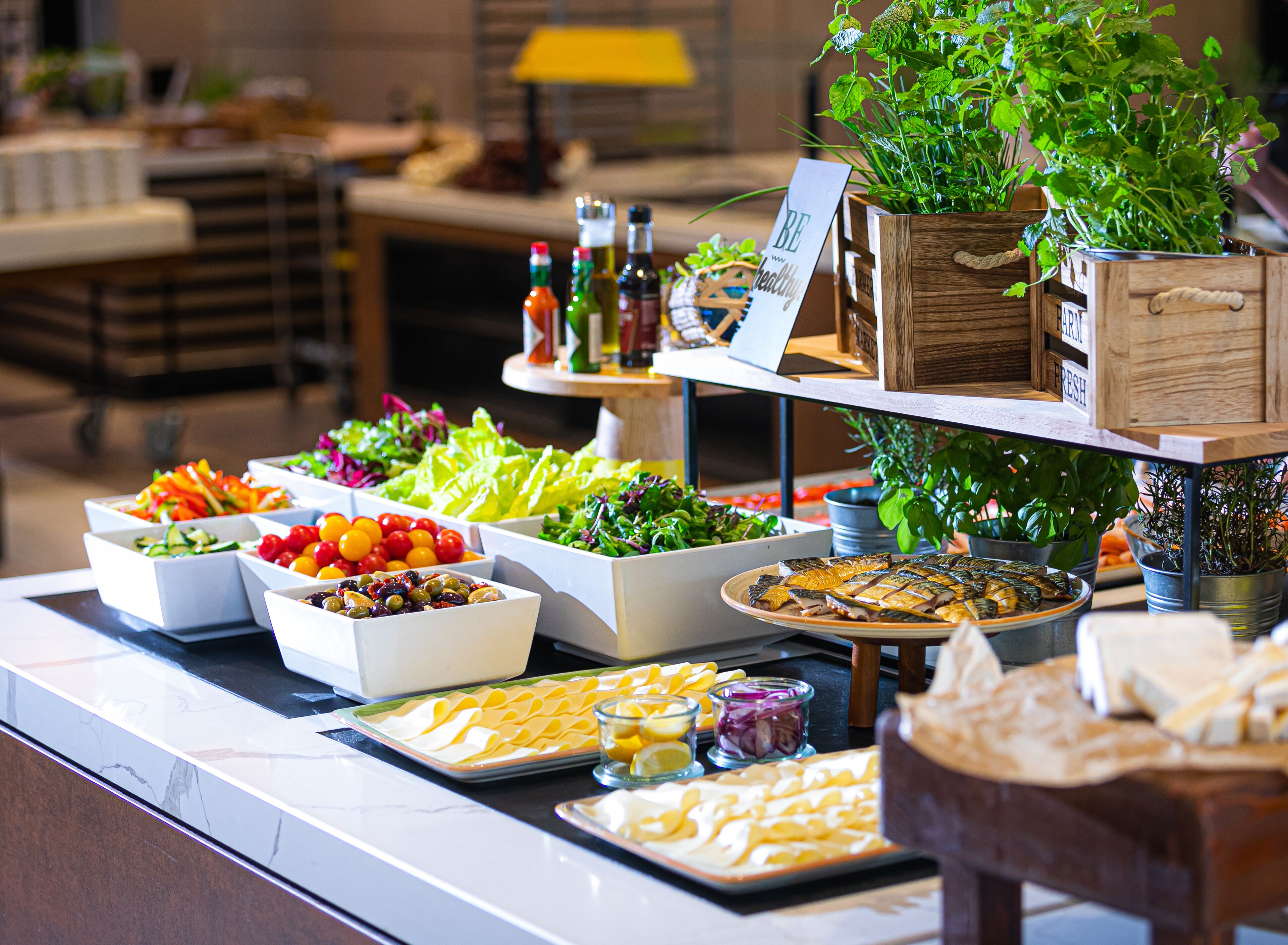 Buffet com diversos alimentos e uma placa com a inscrição 'BE Healthy'.