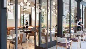 Restaurante moderno com divisórias de vidro, iluminação pendente arredondada e uma variedade de opções de assento, incluindo mesas e cabines.