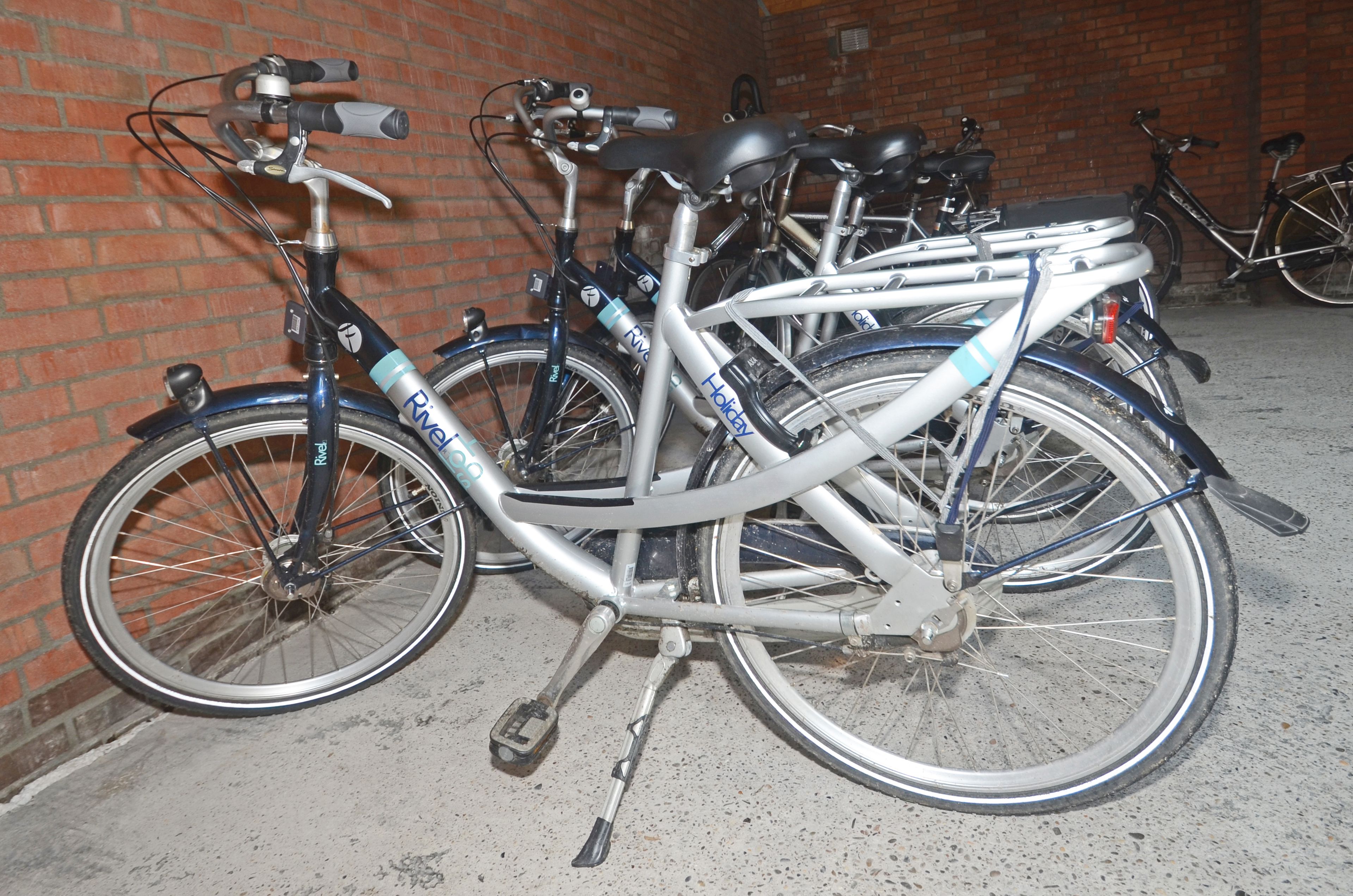 Um suporte para bicicletas com várias bicicletas estacionadas em frente a uma parede de tijolos.