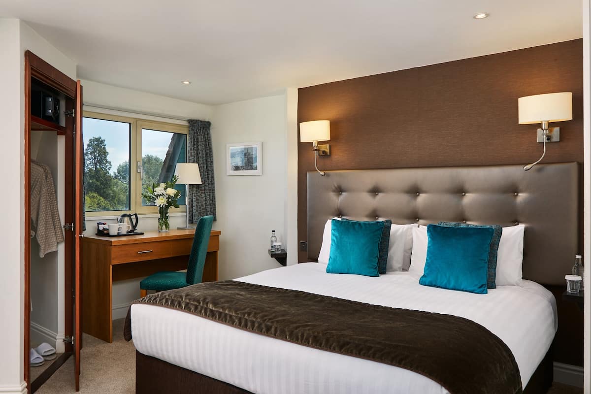 Quarto de hotel com uma cama grande, uma mesa, uma cadeira e um guarda-roupa.