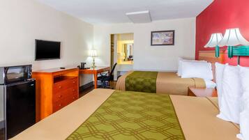 Quarto de hotel com duas camas, uma escrivaninha com abajur, televisão e frigorífico.