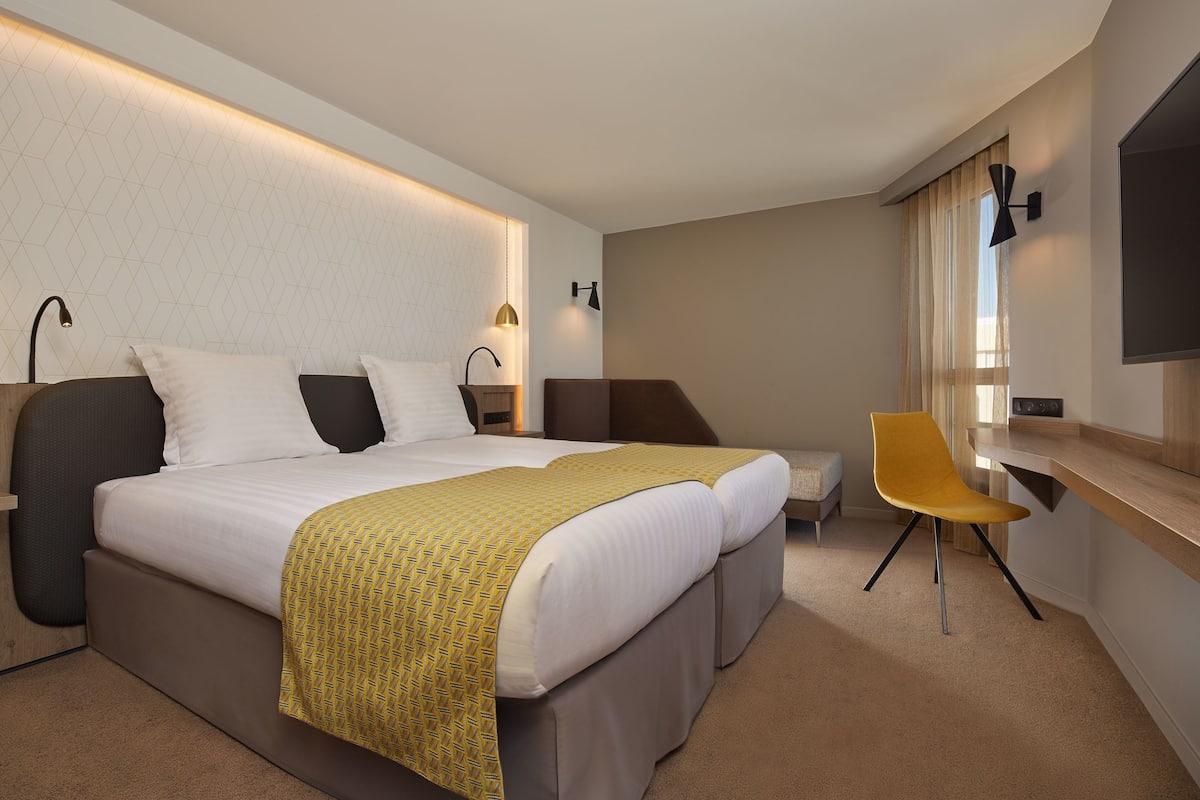 Quarto de hotel moderno com uma cama grande, uma escrivaninha e uma cadeira.