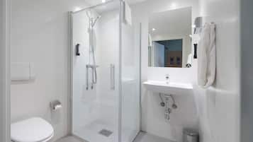Uma casa de banho moderna com chuveiro em cabine de vidro, lavatório branco e sanita.