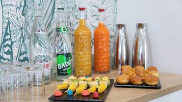 Uma mesa com diversos alimentos, incluindo espetos de fruta e doces, além de várias garrafas de bebidas.