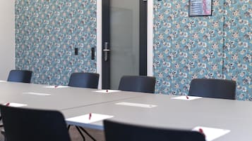 Uma sala de conferências com uma mesa comprida, cadeiras e uma porta.