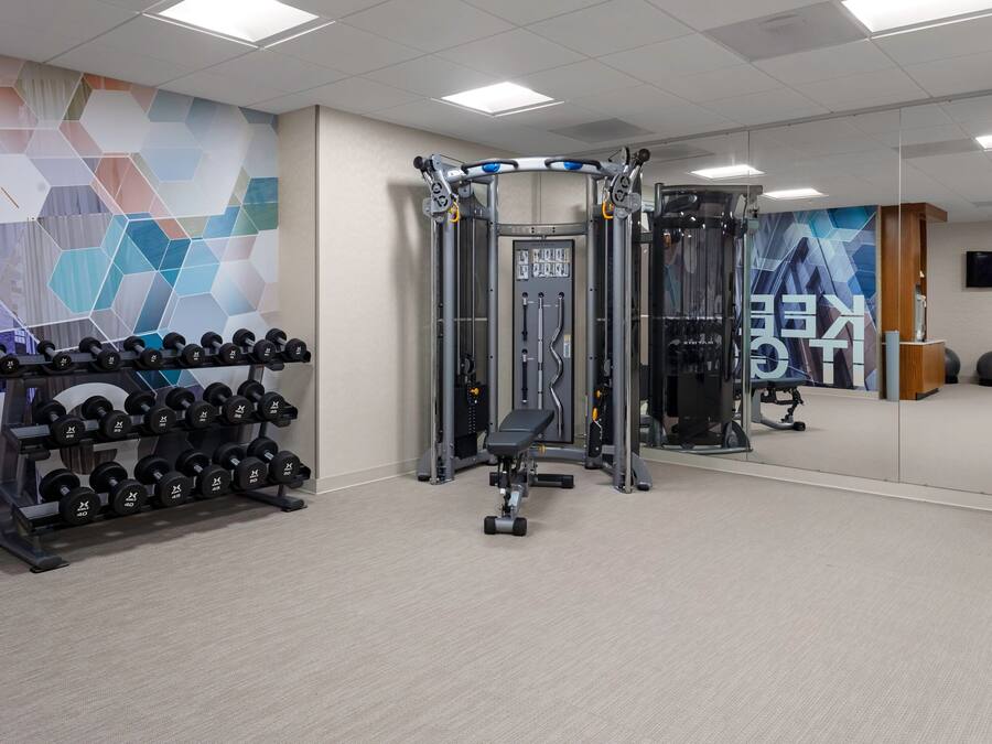 Uma academia com equipamentos de musculação, incluindo um banco de supino e um espelho.