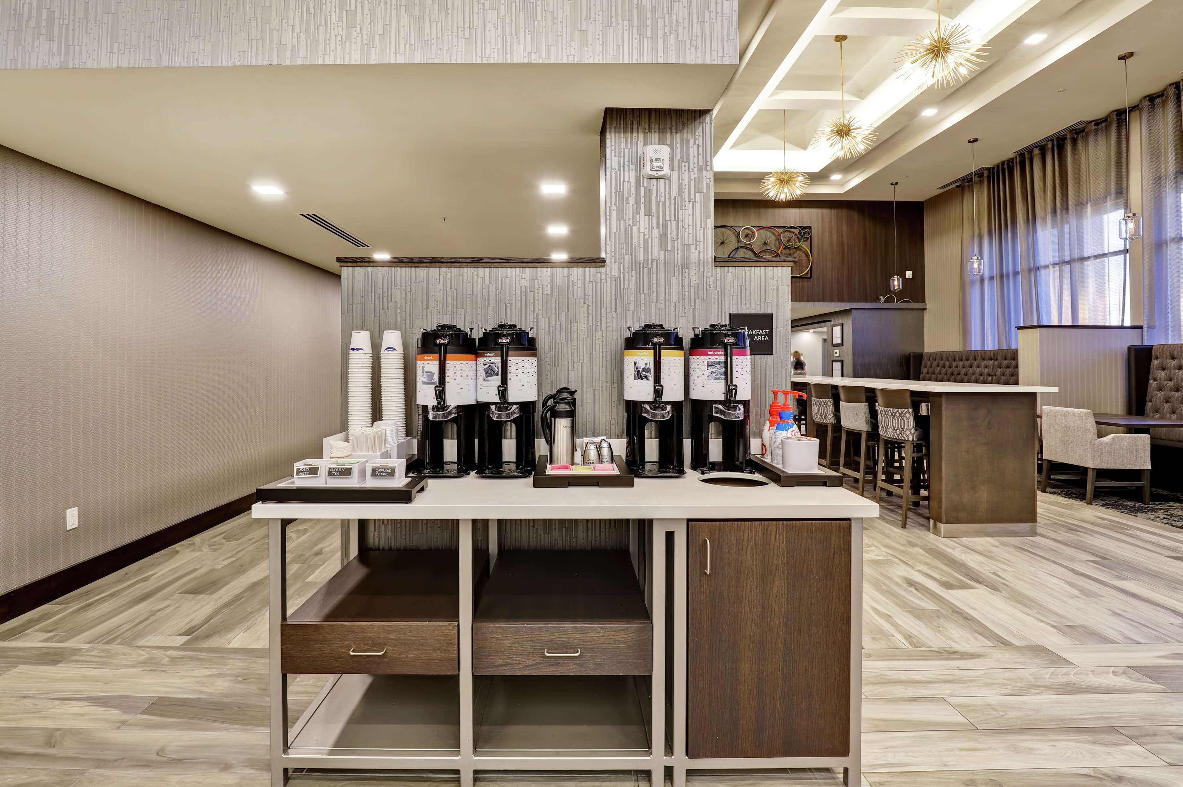 Um saguão de hotel com um espaço para café, área de estar e balcão de recepção.