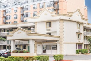 Um edifício residencial de vários andares com fachada bege, varandas e portão.