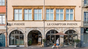 Um edifício com duas fachadas, uma delas com o nome "LE PHENIX" e a outra "LE COMPTOIR PHENIX".