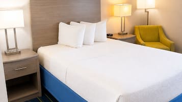 Quarto de hotel com uma cama grande, duas mesas de cabeceira, uma cadeira e duas luminárias.