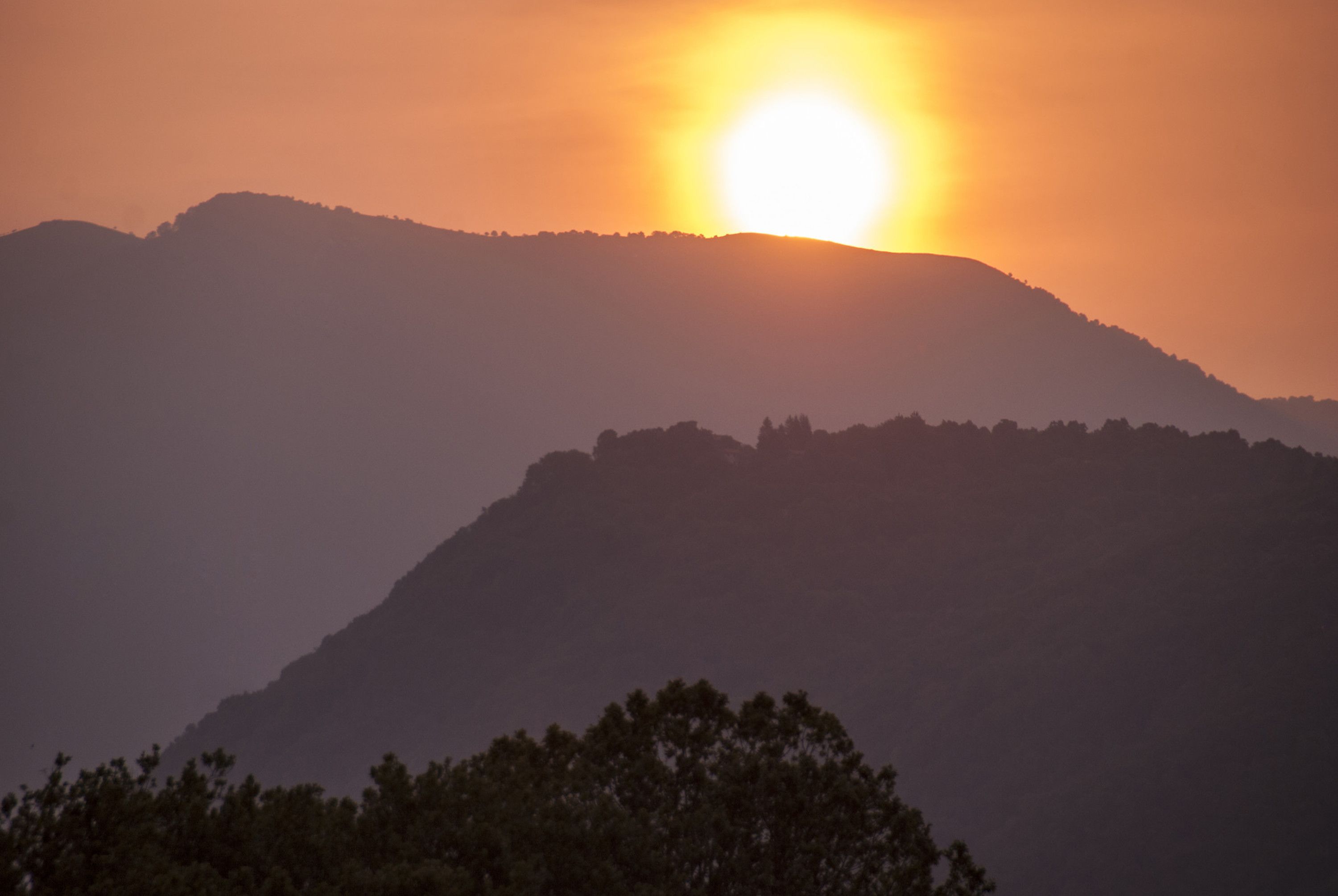 Silhueta de montanha com o sol se pondo ou nascendo ao fundo.
