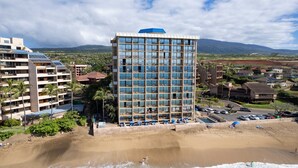 Um hotel na praia com vários andares, piscina e vista para a praia e montanhas.