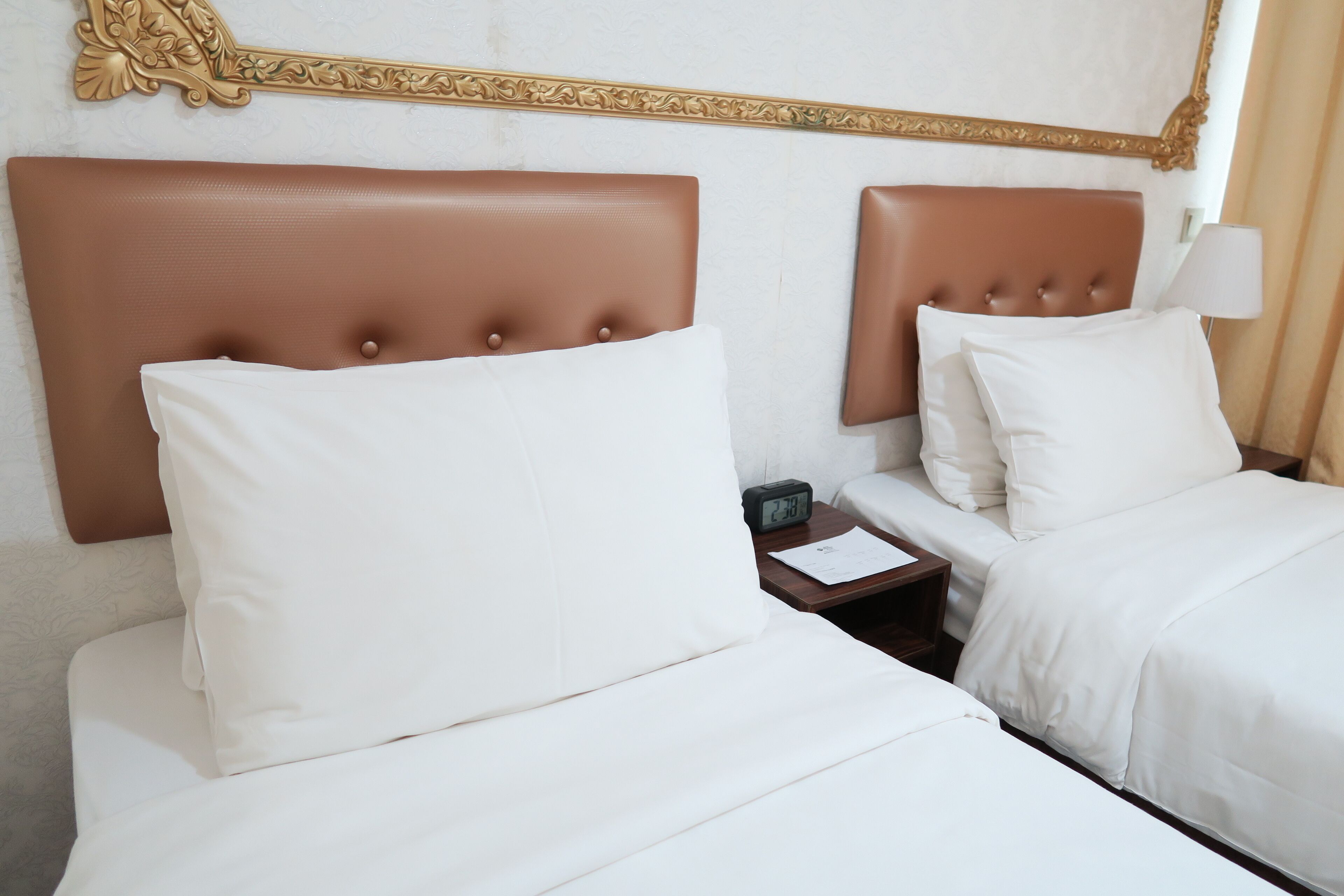 Quarto de hotel com duas camas, cada uma com cabeceira marrom e roupa de cama branca.