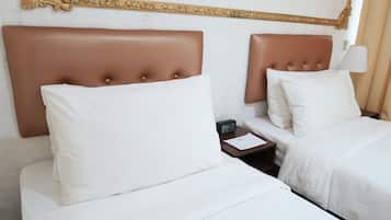 Quarto de hotel com duas camas, cada uma com cabeceira marrom e roupa de cama branca.