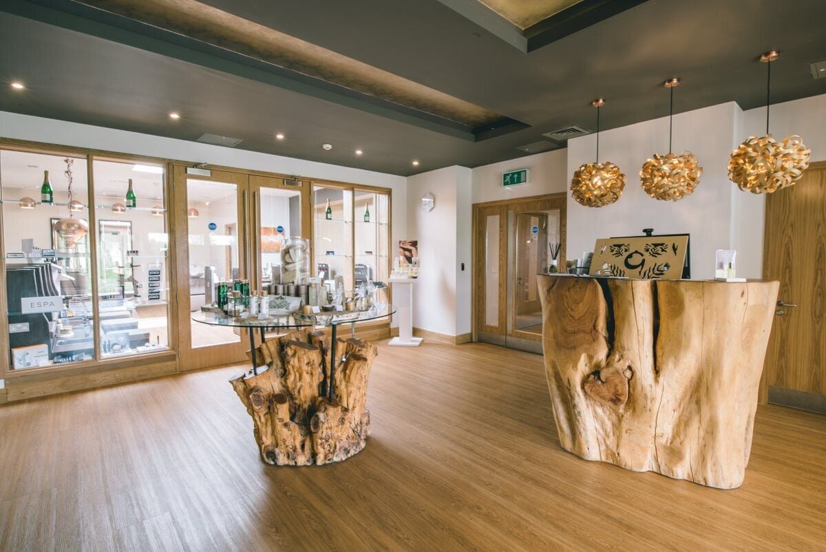 Um interior moderno com uma mesa de centro de madeira, um balcão de recepção em madeira e uma vitrine de vidro.