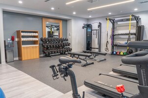 Academia com esteiras, bancos de musculação e suporte para agachamento.