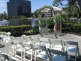 Cerimônia de casamento ao ar livre com cadeiras brancas e um gazebo branco.