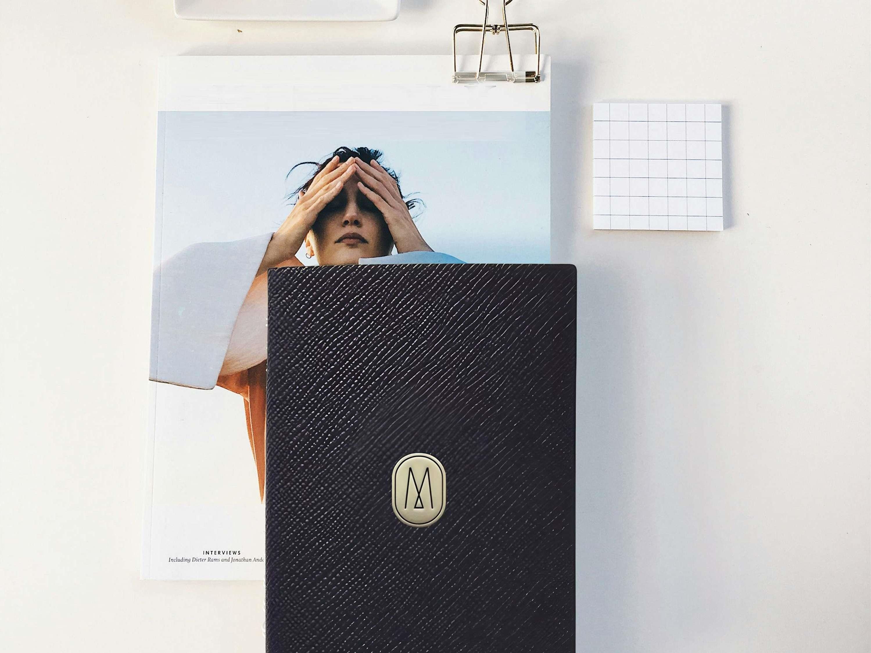 Um laptop preto com um logotipo, um quadro branco com linhas de grade e uma parede branca.