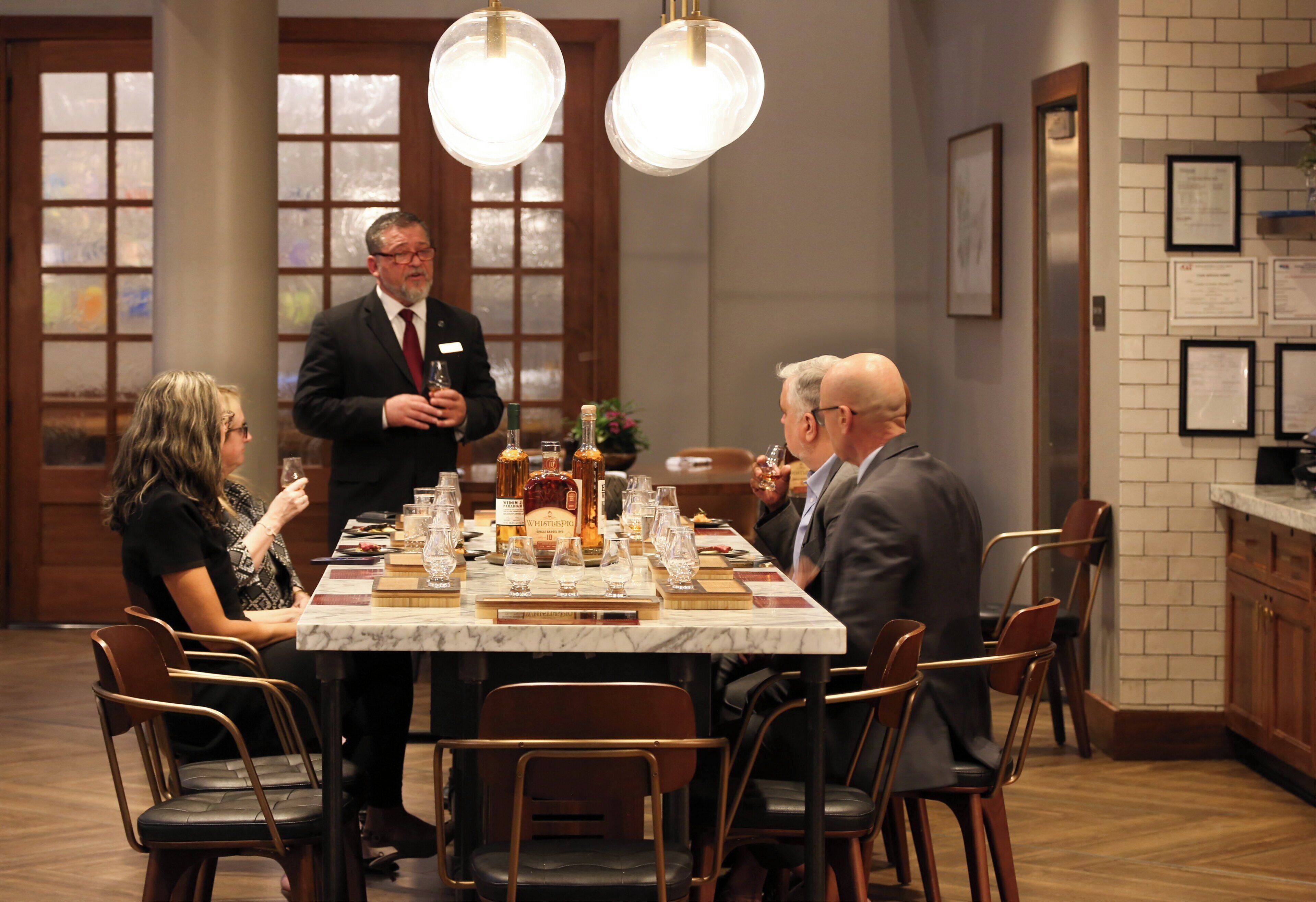 Uma sala de jantar formal com uma mesa de mármore, várias cadeiras e luminárias pendentes.
