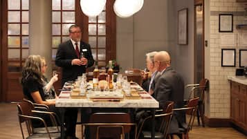 Uma sala de jantar formal com uma mesa de mármore, várias cadeiras e luminárias pendentes.