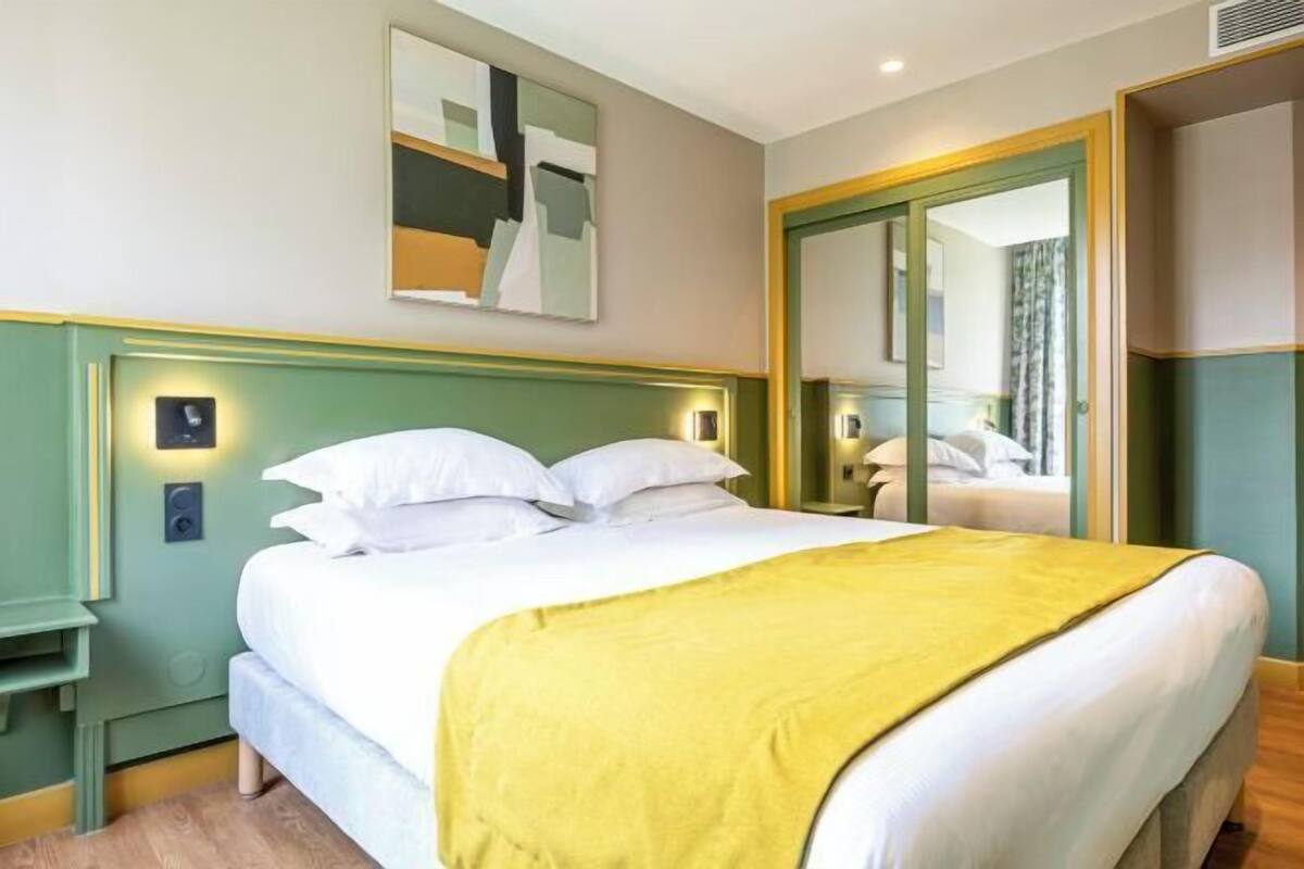 Quarto de hotel com cama, mesa de cabeceira e espelho.