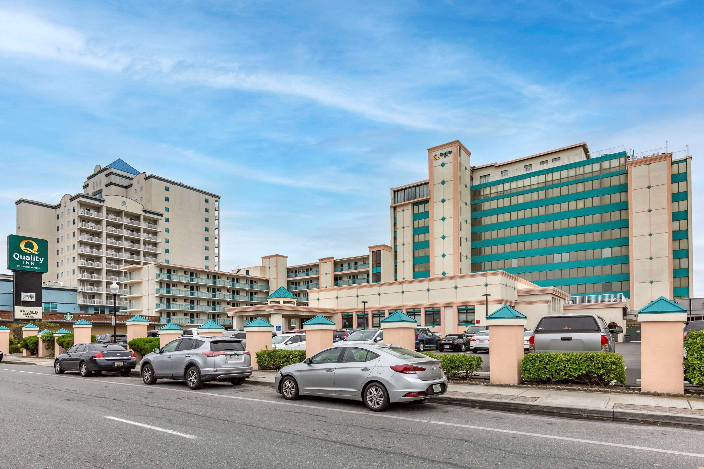 Um hotel com vários edifícios, um estacionamento e diversos carros estacionados na frente.