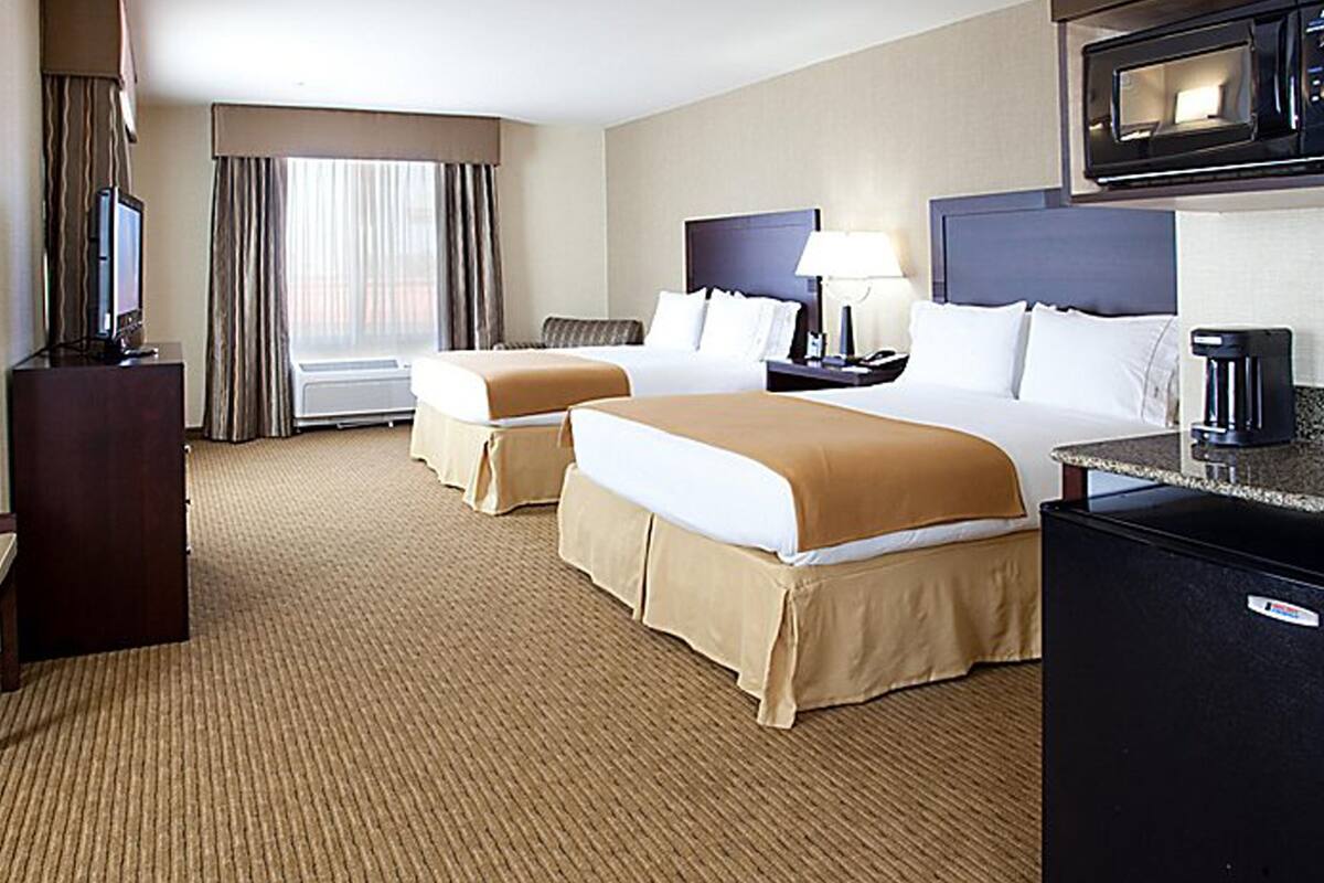 Quarto de hotel com duas camas, televisão, escrivaninha, cafeteira e janela com cortinas.