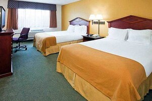 Quarto de hotel com duas camas, uma escrivaninha, uma cadeira e uma janela com cortinas.