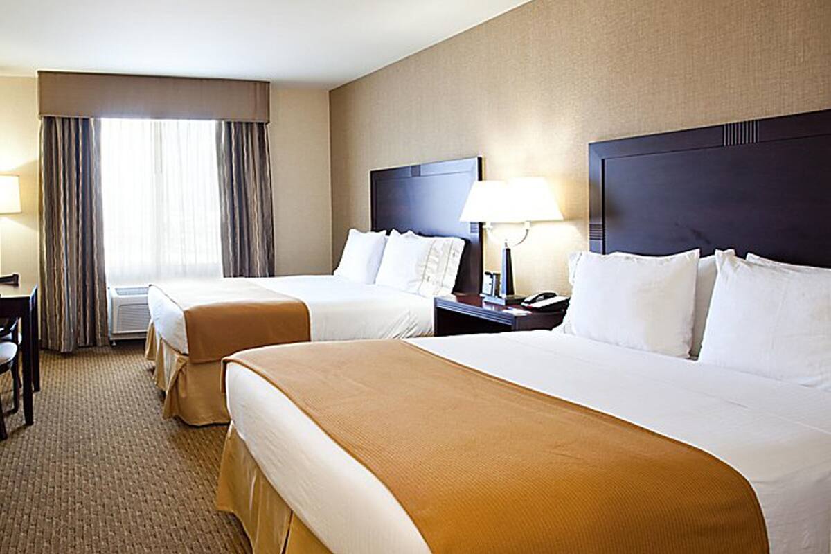 Quarto de hotel com duas camas, uma escrivaninha e uma cadeira.
